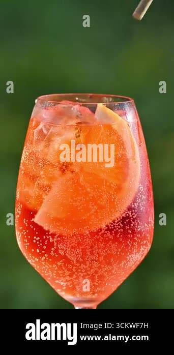 glass of fresh refreshing aperol spritz cocktail against a green ...