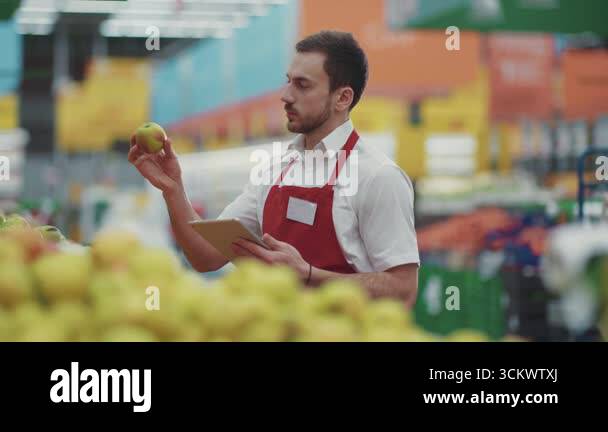 Smiling seller man use tablet computer in supermarket vegetable ...