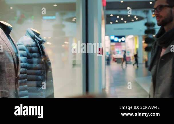 Close up young attractive man looking at shop window with mens suits in ...