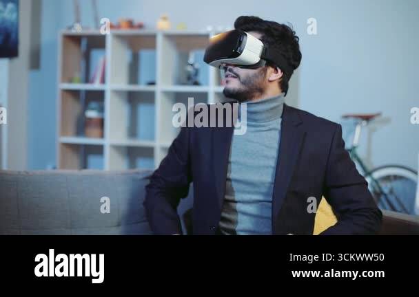 Young man in a stylish outfit wears the virtual reality glasses. Amazed ...