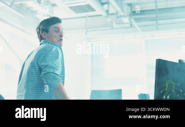 Young handsome guy flapping fire extinguisher on smoking computer ...