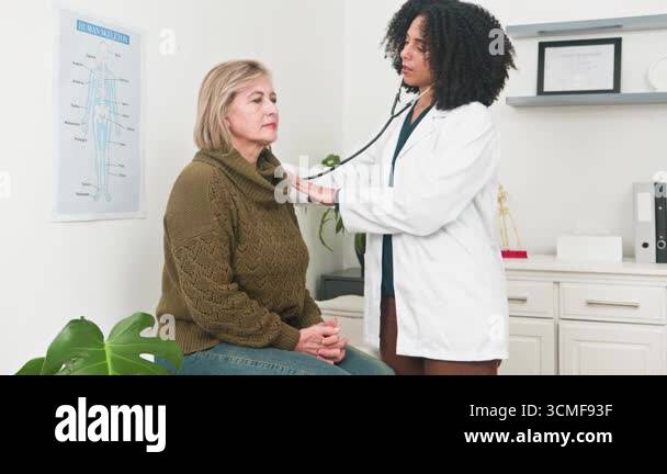 A diverse female doctor meticulously conducts a medical examination on ...