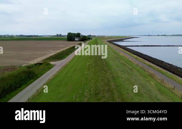 A calm coastal landscape with green fields, winding paths, and a ...