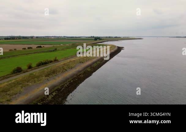 A calm coastal landscape with green fields, winding paths, and a ...