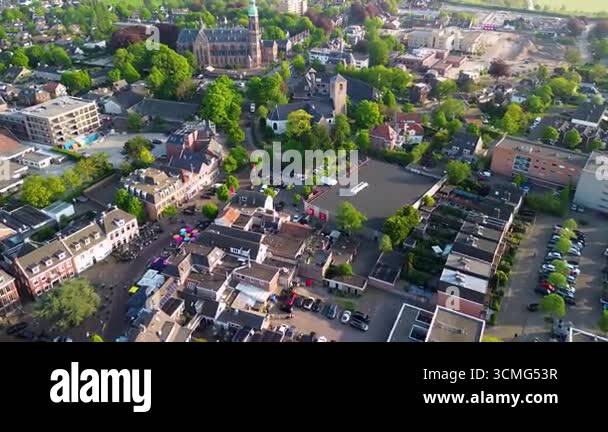 Aerial drone view of a town square with a parking lot, cars, trees, and ...