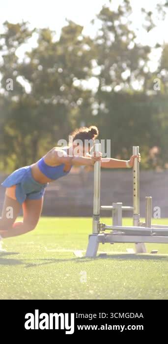 A dedicated athlete performs an intense sled push on sunny turf to ...