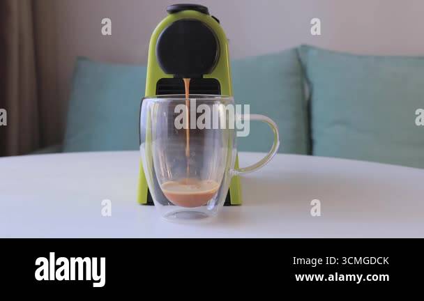 Fresh espresso coffee being poured into a transparent glass cup from a ...