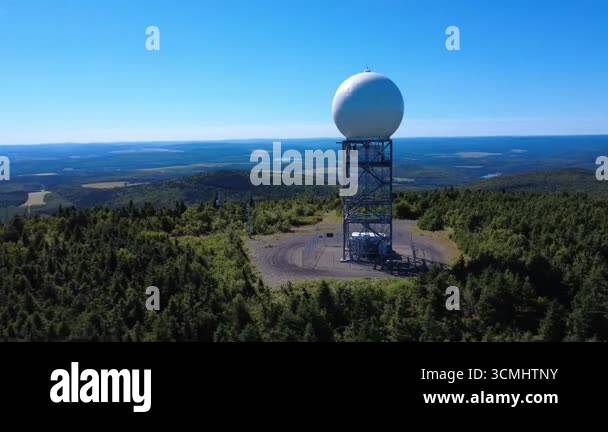 Drone footage circling a mountaintop weather radar tower, offering ...