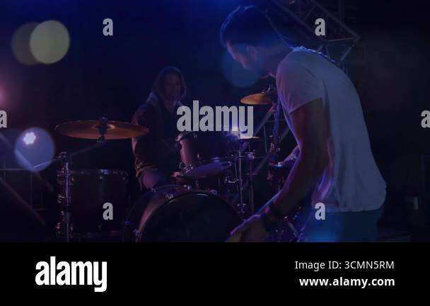 Drummer tapping beat, starting light beams while guitarist strumming ...