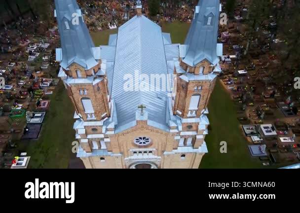 Drone captures a historic red brick church with twin spires, blue roof ...