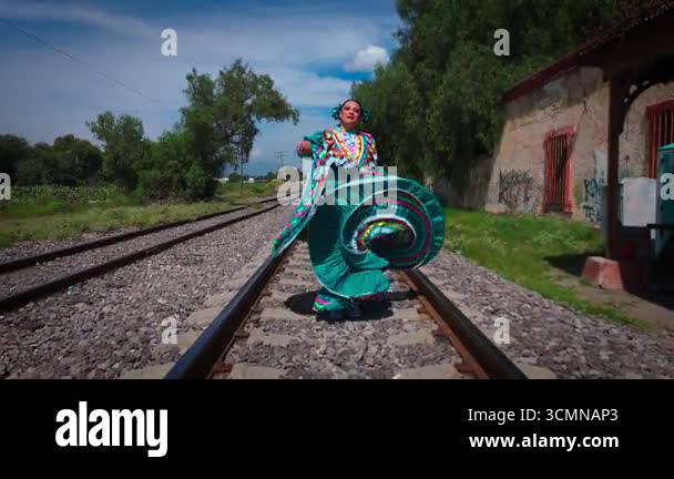 A Mexican folkloric dancer wearing a colorful traditional dress ...