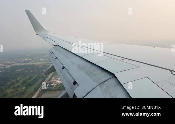 Scenic passenger view of airplane wing flying over city landscape in ...