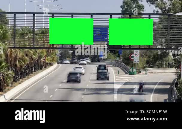 Rush of traffic on highway in city with green screen on the overhead ...