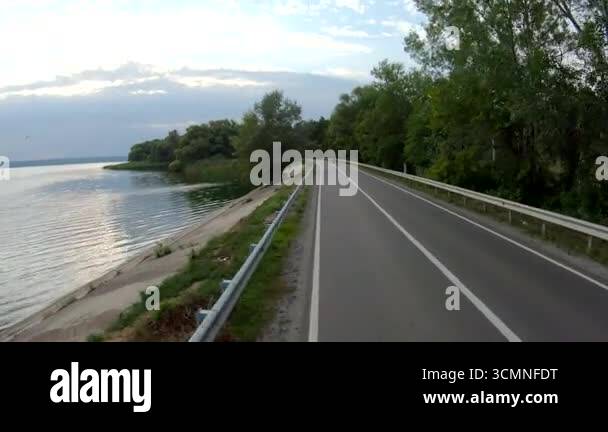 Motorcyclist races his motorcycle on country road at dam. Man in helmet ...