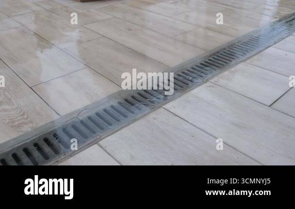 Clogged street drain with standing rainwater on tiled pavement. Water ...