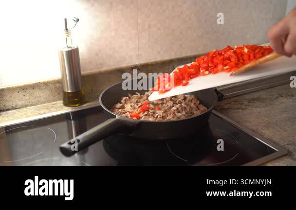 Cooking process with diced sweet pepper being added into a frying pan ...