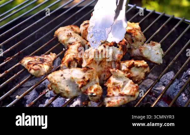 Marinated chicken fillet pieces are being grilled on charcoal outside ...