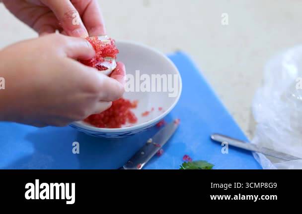 Hands extracting finger lime pulp into a bowl on a kitchen counter ...