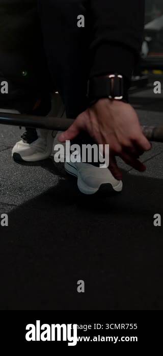 In a gym setting a man focuses on wrapping deadlift straps around a ...