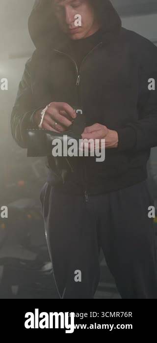 focused man in a black hoodie adjusts barbell row straps as he prepares ...