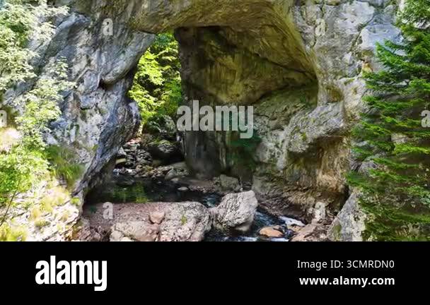 Drone aerial view of a natural stone arch formation with river stream ...