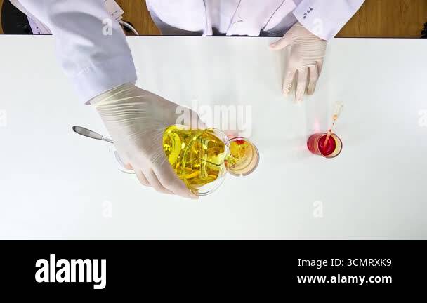 Hands in gloves mix liquids in a lab setting, creating a vibrant lava ...