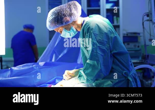Female surgeon leaning over the patient at operation. Professional uses ...