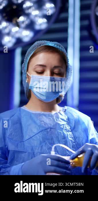 Female scrub nurse holding an oxygen mask. Medic smiles to camera ...