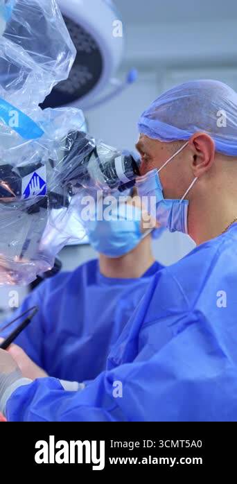 Tense face of the male Caucasian doctor looking at microscope. Surgeon ...