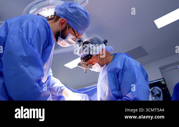 Two cooperating surgeons work at surgery. Low angle view at the doctors ...