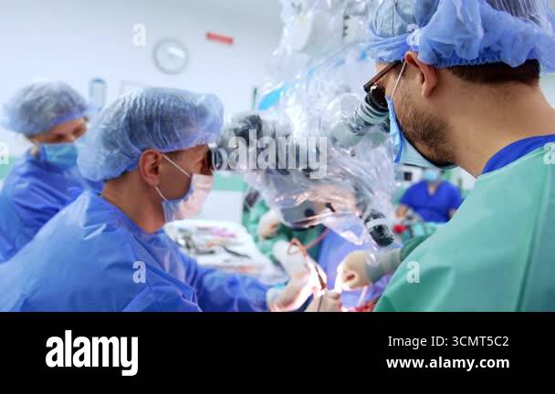 Doctors performing neurosurgery look at microscope. Brain tumor removal ...