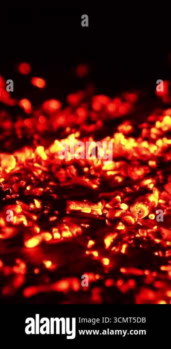 Smoldering red embers scattered on the ground. Smoke goes up and ...