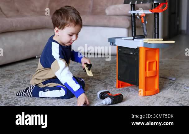Child engaged in pretend play with tools. A young child sits on the ...