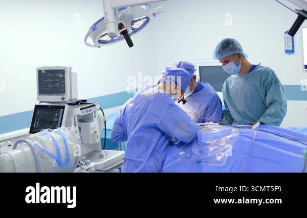Three male medics performing operation in modern surgical room. Doctor ...