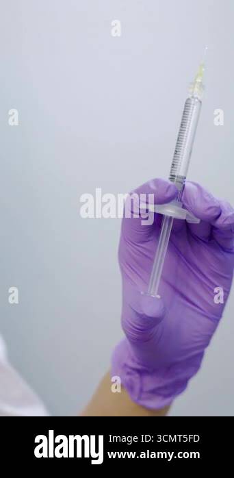 A beautician in purple gloves is holding an injection of a botulinum ...