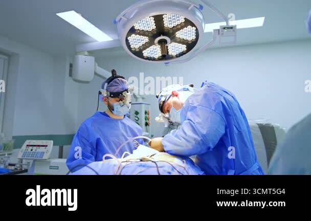 Distancing from two surgeons operating a patient. Female scrub nurse ...