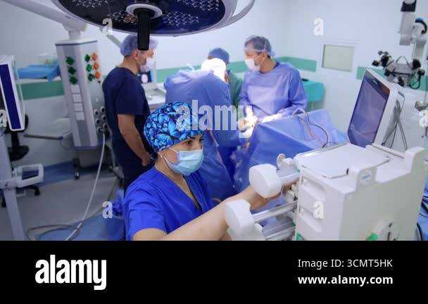 Female medic stands at the medical equipment in surgery room. Team of ...