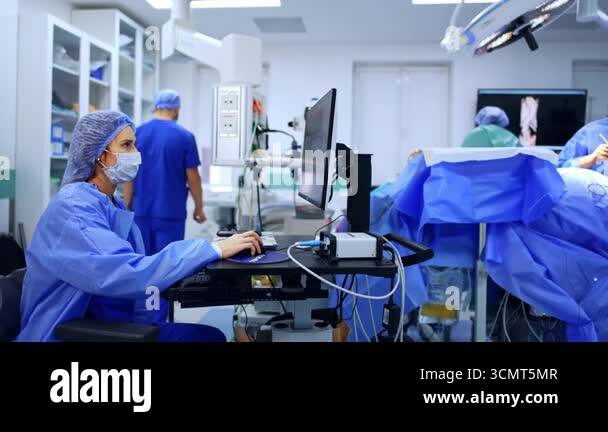 Surgeon uses computer in operating room. A medical professional works ...