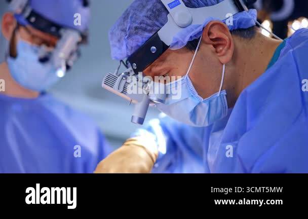 Surgeons in complex operation. Two surgeons focus intently on a complex ...