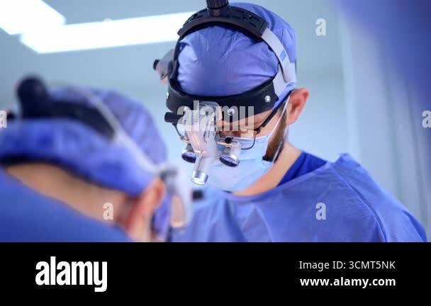 Surgeon in delicate operation. A skilled surgeon focuses intently on a ...