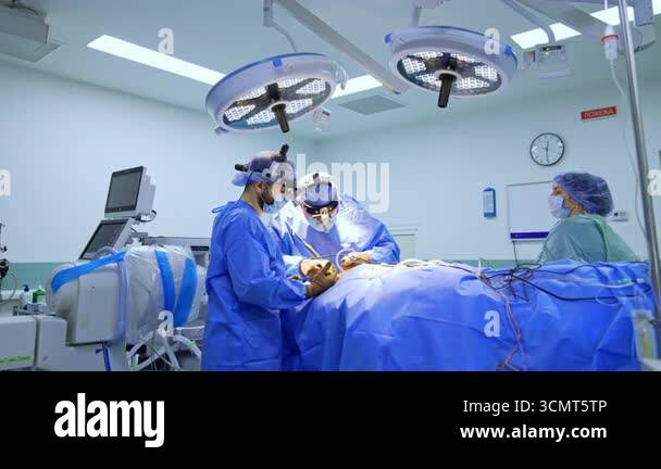 Approaching the operating table in surgery room where the operation takes place. Two male ...