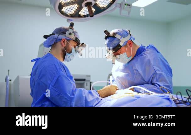 Surgeons in the operating room. Two surgeons in blue scrubs focus on ...