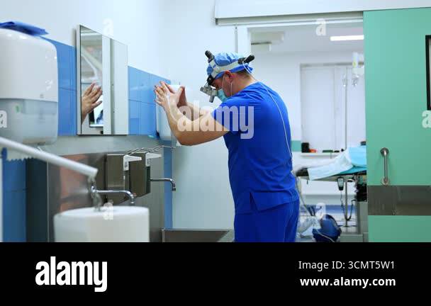 Surgeon readies for surgery. A surgeon wearing scrubs and a surgical ...