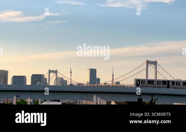 Elevated train traversing Tokyos cityscape at sunset, with Rainbow ...