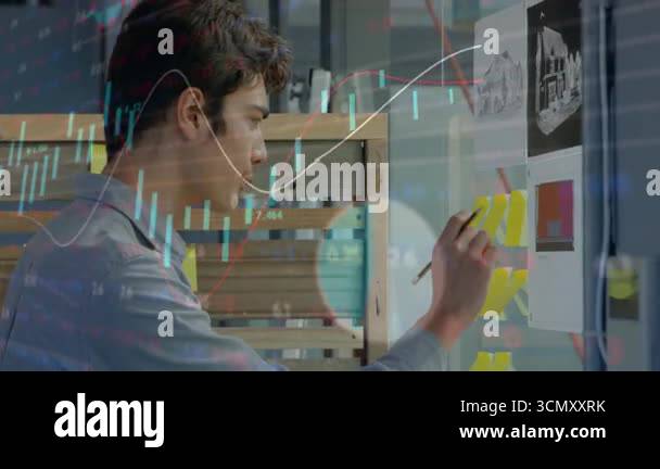 Designer selecting sticky note, writing annotation on board while ...