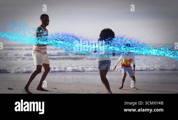 Girl raising beach ball overhead initiating family catching game on wet ...