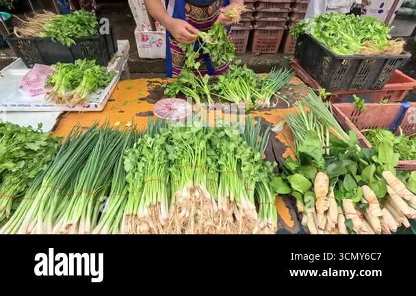 Vendor arranging vegetables at a busy market stall Stock Video Footage ...