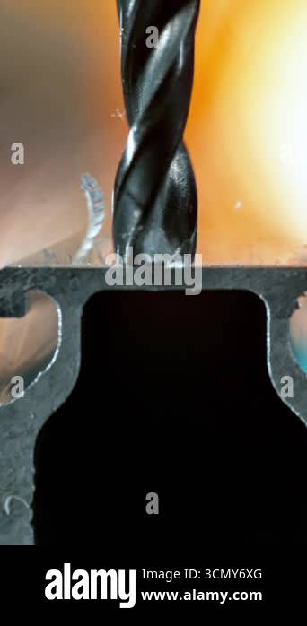 Super slow motion of detail of a drill bit drilling into aluminium pipe ...