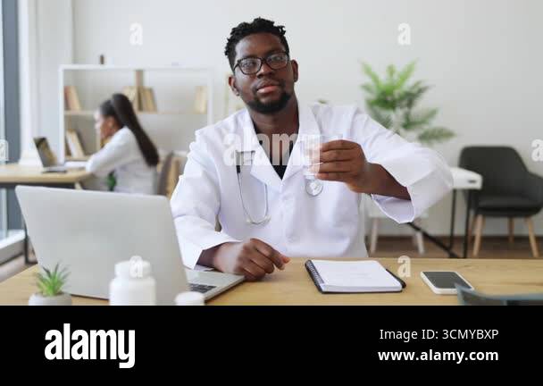 Male doctor wearing white coat sitting at workplace and explaining ...