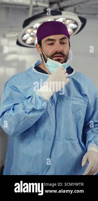 A vertical video of a surgeon in scrubs and surgical cap, preparing for ...